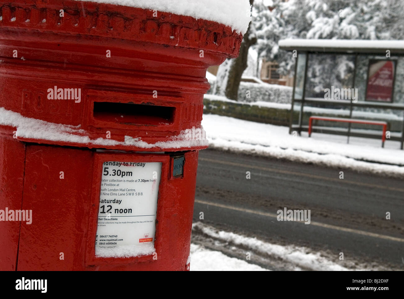 Red letter/post box after heavy snowfalls in London, with bus stop in ...