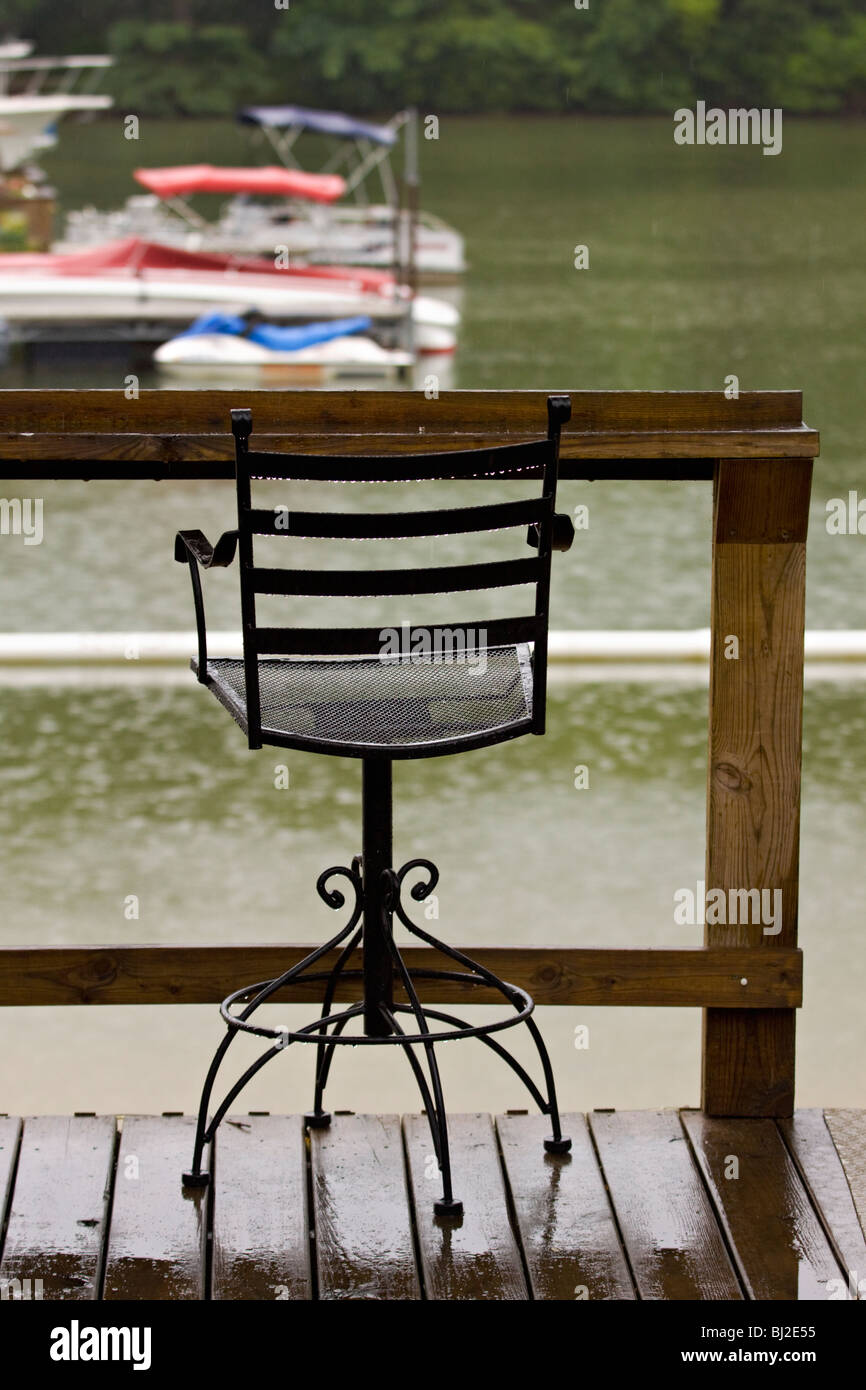 A high stool on a deck bar at a marina overlooking the lake and boats ...