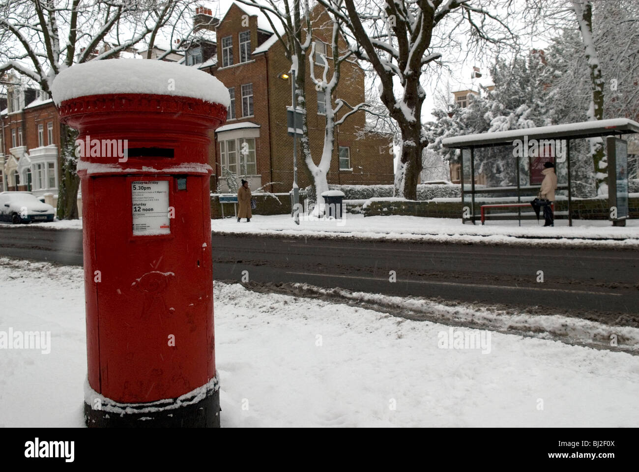 Red letter/post box after heavy snowfalls in London, with bus stop in ...