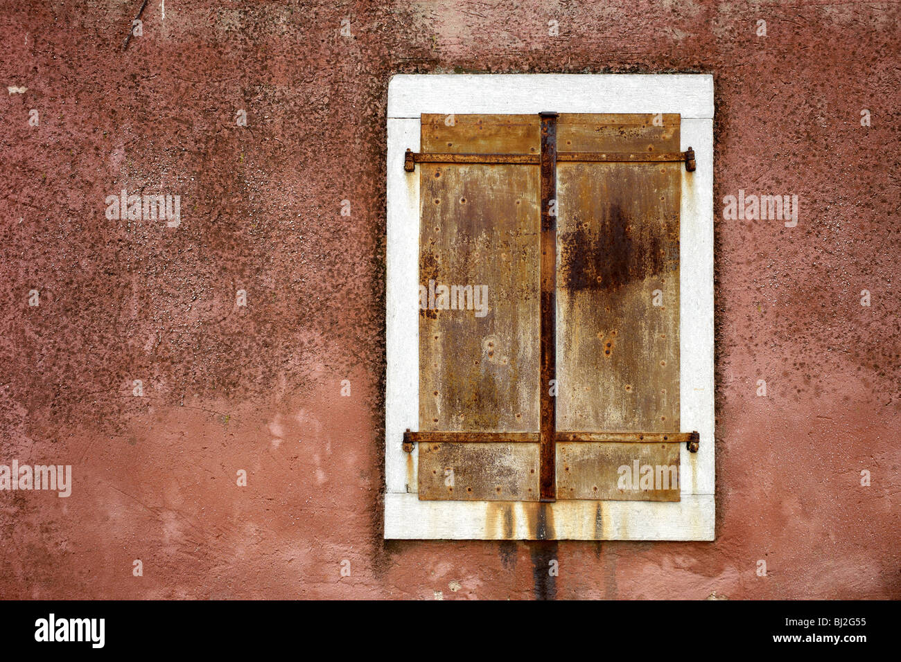 Rusty closed iron window with white border made of sotne. Wall has nice ...