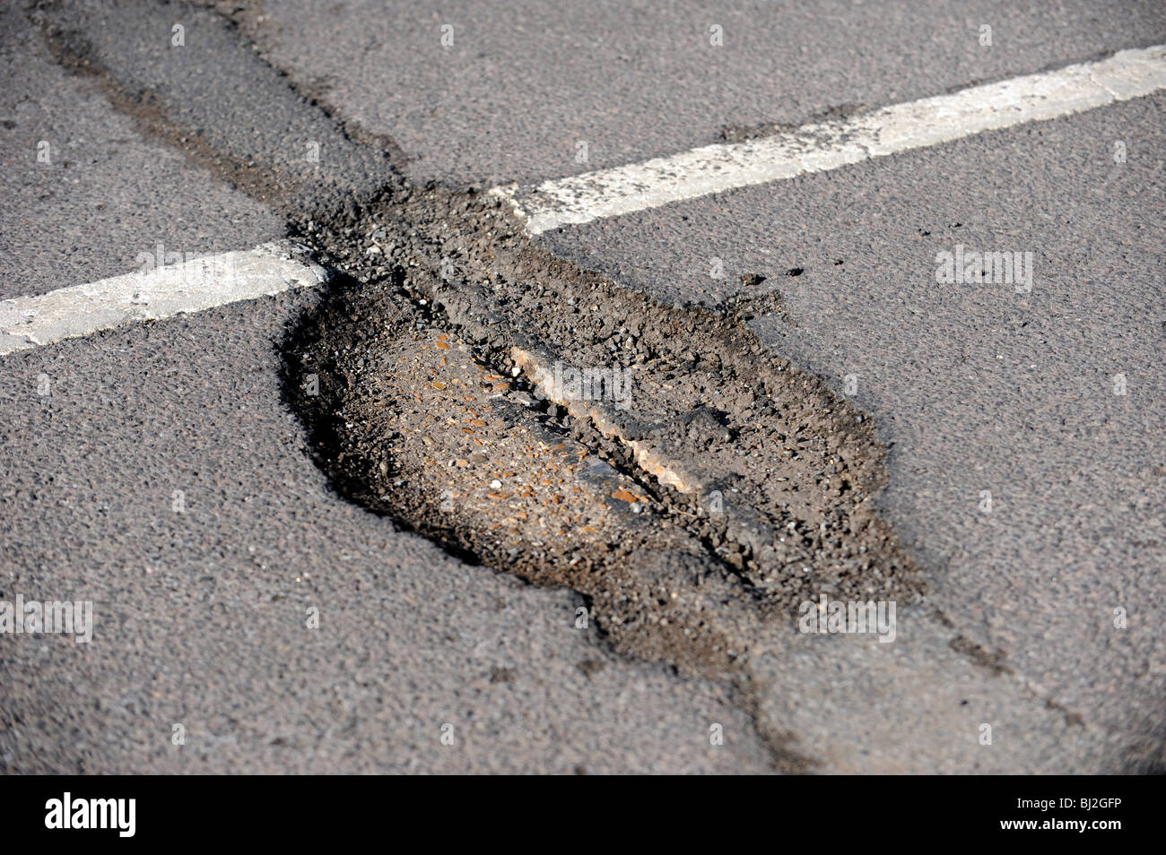 A deep pothole in the road caused by the recent snow and freezing ...