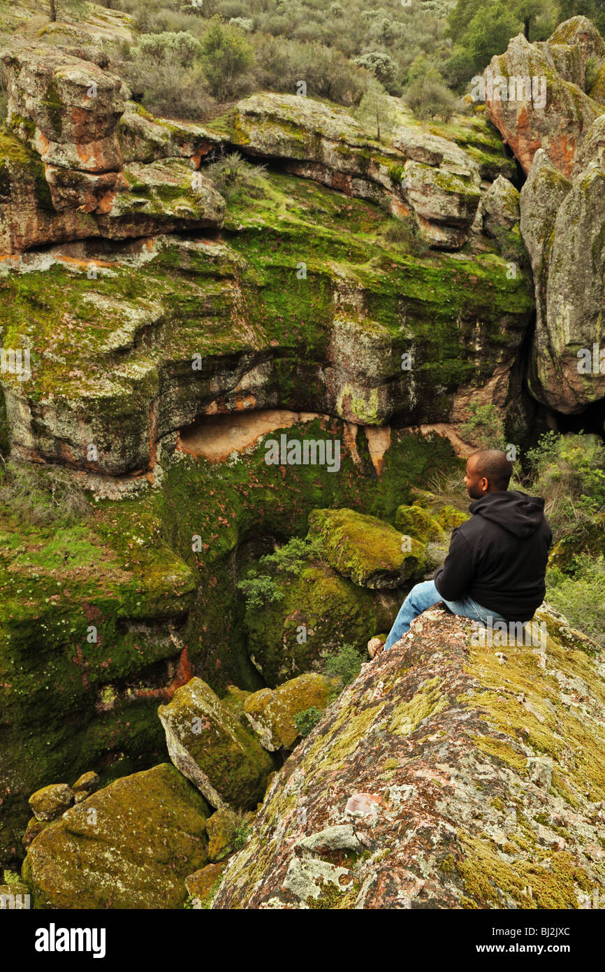 Resting hiker looks at moss covered cliff Stock Photo - Alamy