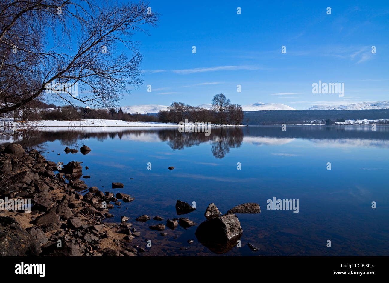 The shore of Loch Rannoch with a backdrop of winter snow capped ...