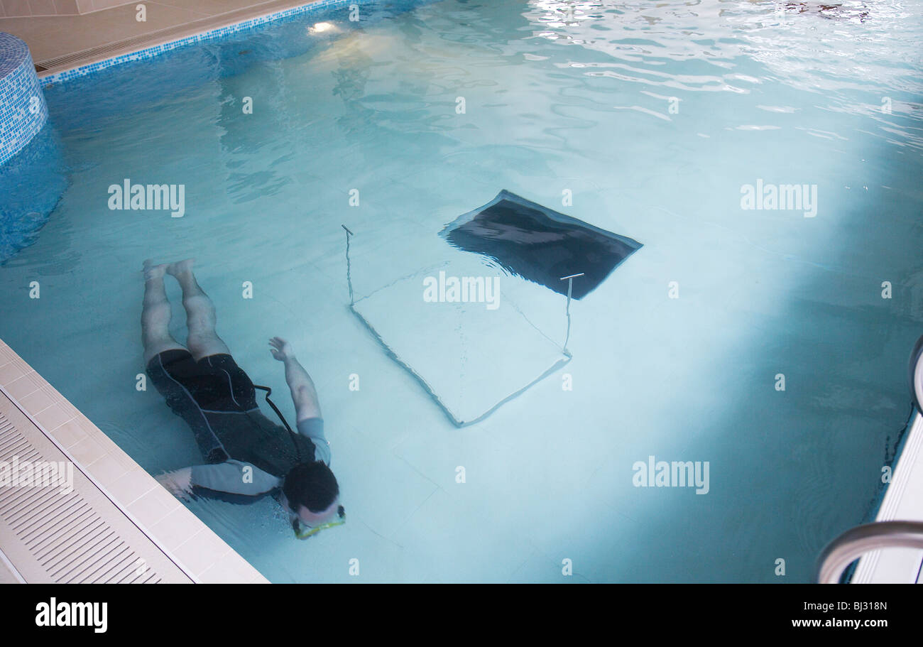 Man doing maintenance on hydraulics on a concealed swimming pool with a ...