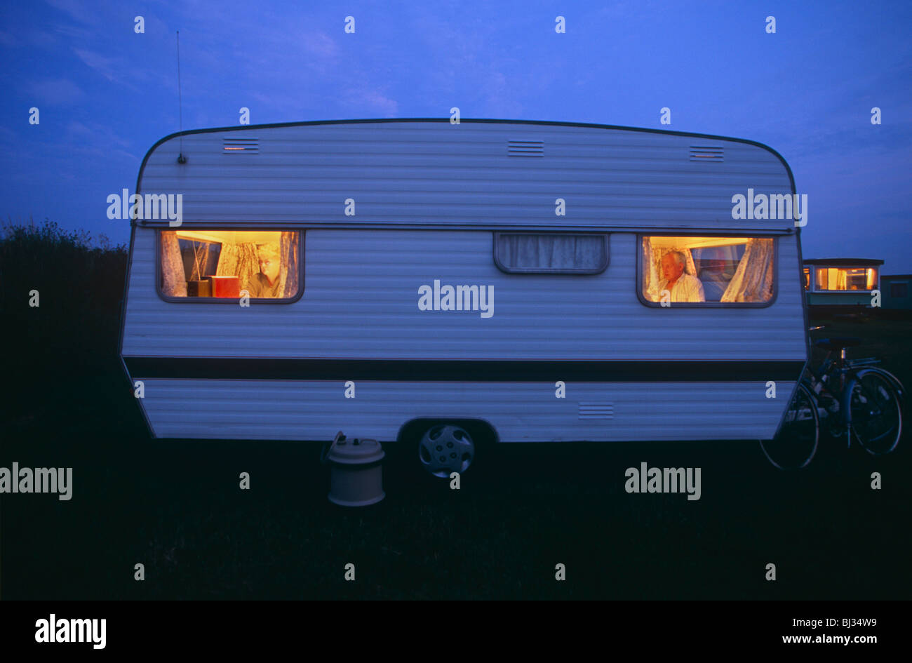 Warm orange glow of two caravan campers can be seen through both the ...