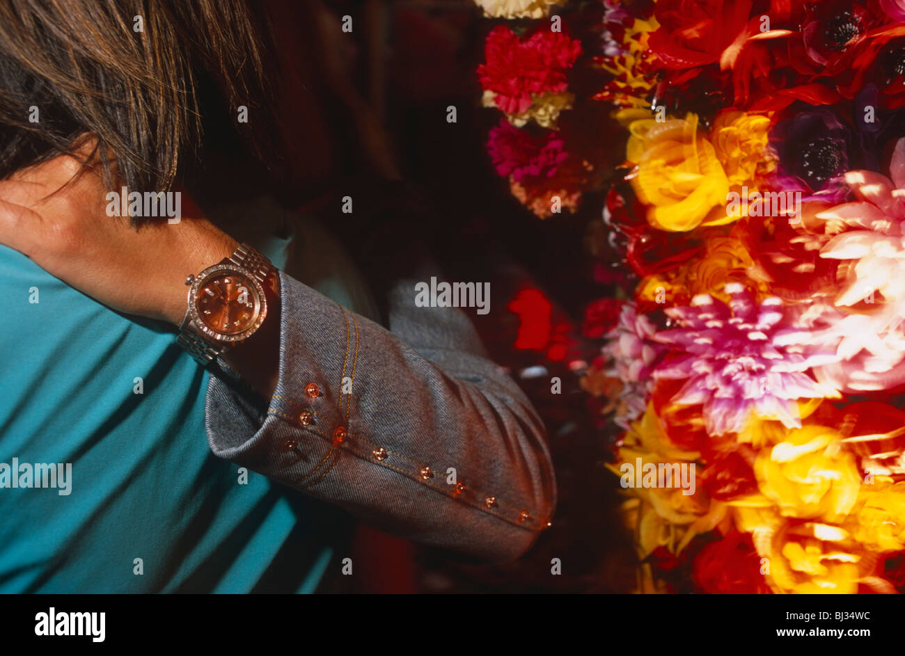 A party-goer with an expensive-looking wrist watch, drapes his arm over ...