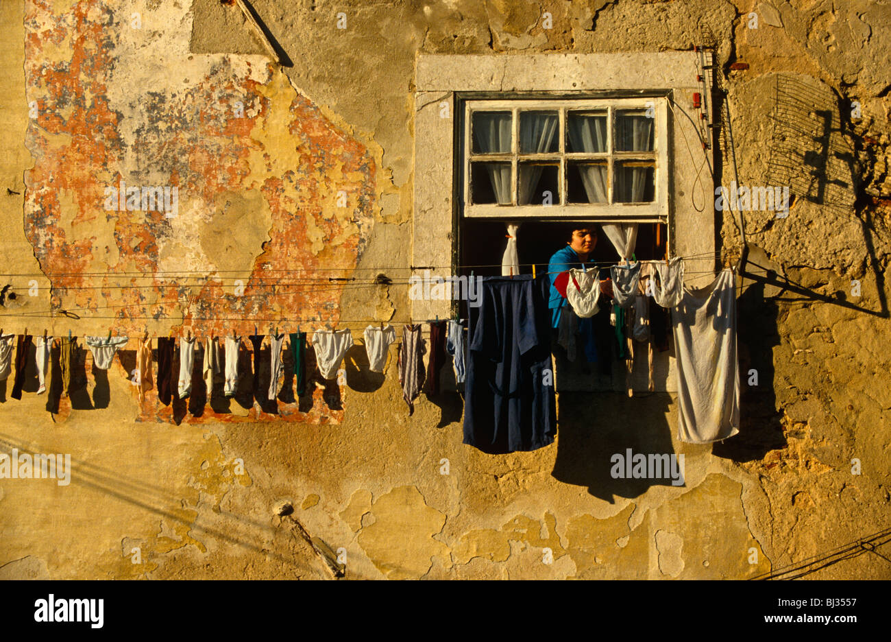 High above the streets of Old Lisbon, a Portuguese lady leans out of ...