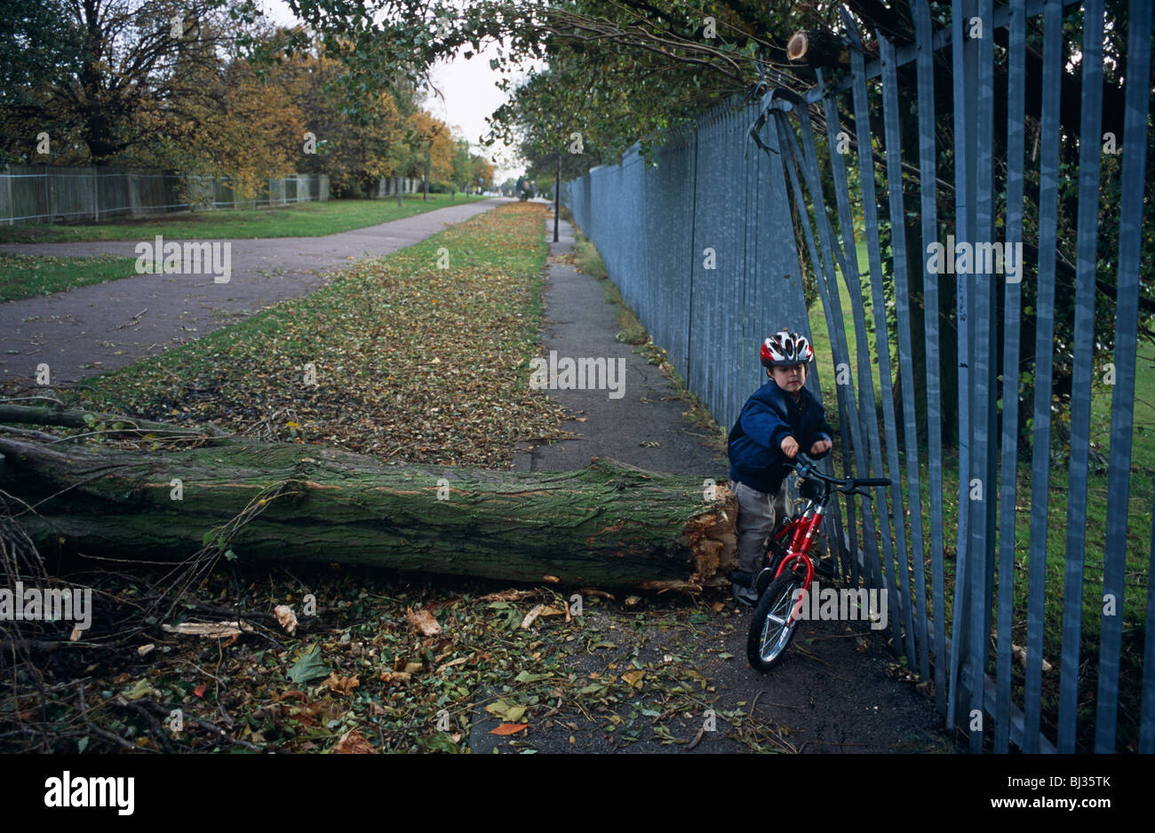 A young boy edges through a gap between some railings and the end of a ...
