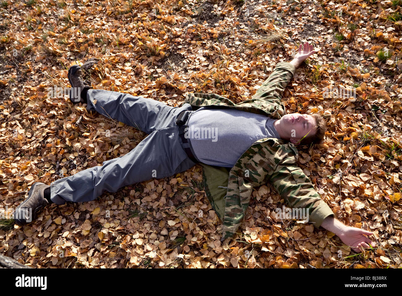 Man sleeping on the field with yellow leaves Stock Photo - Alamy
