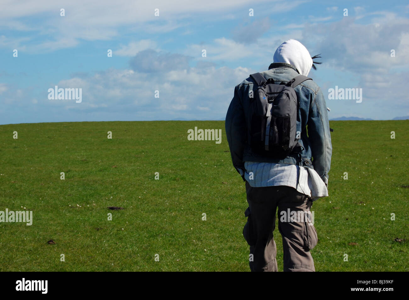 Young man hiking alone through a field in Kaikoura, New Zealand Stock ...