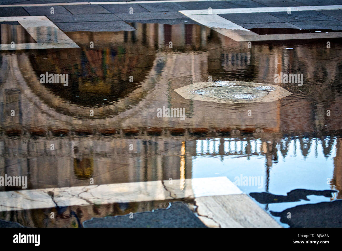 Acqua Alta water rising through a drain reflecting the Basilica di San ...