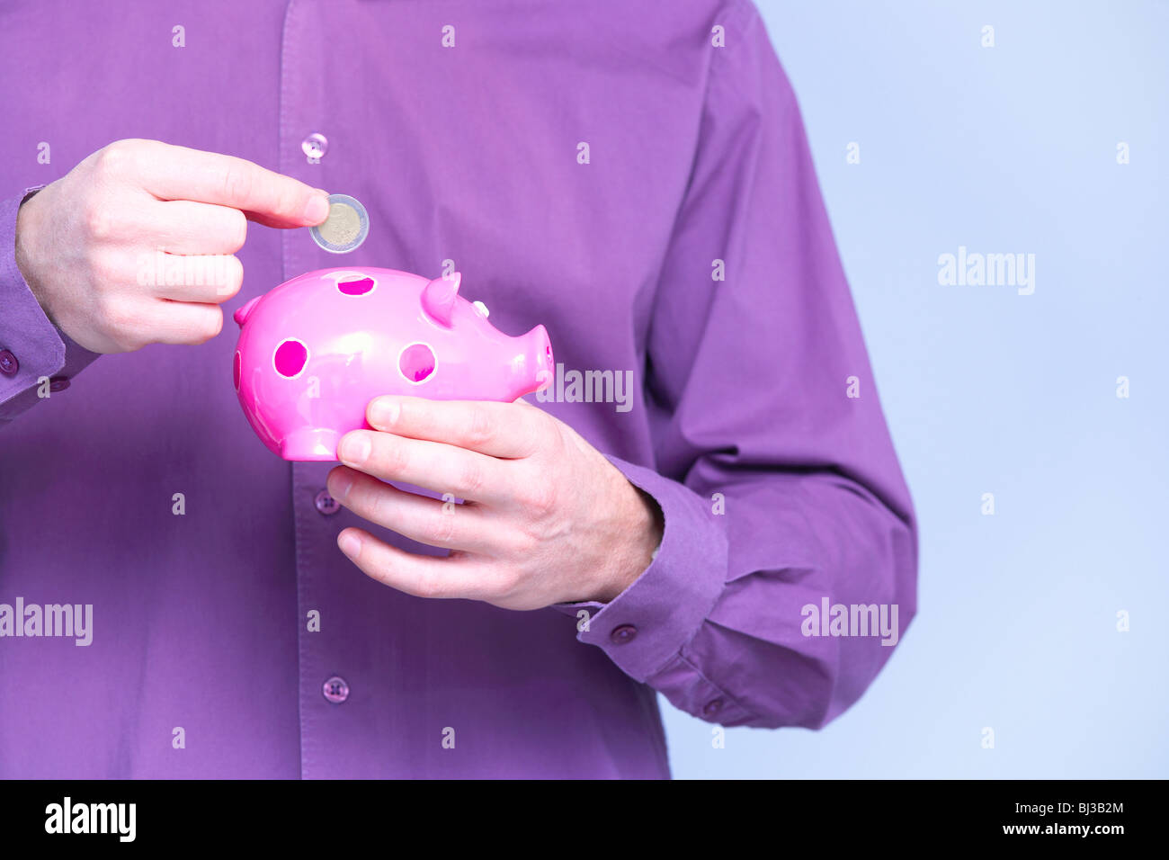 man dropping a coin in a piggy box Stock Photo - Alamy