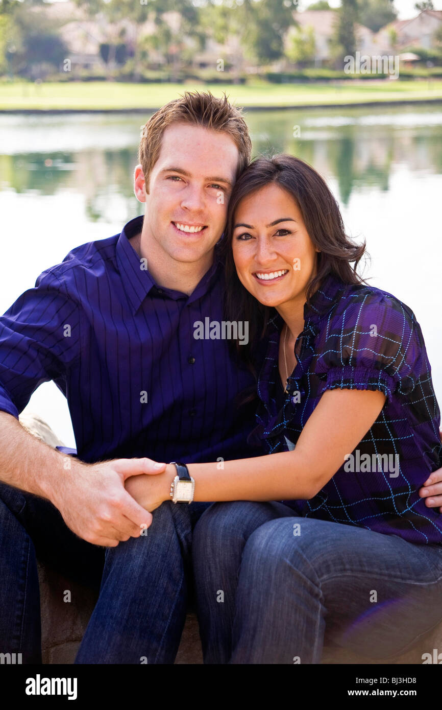 Close up portrait Young couple cheeks together at lakeside park ...