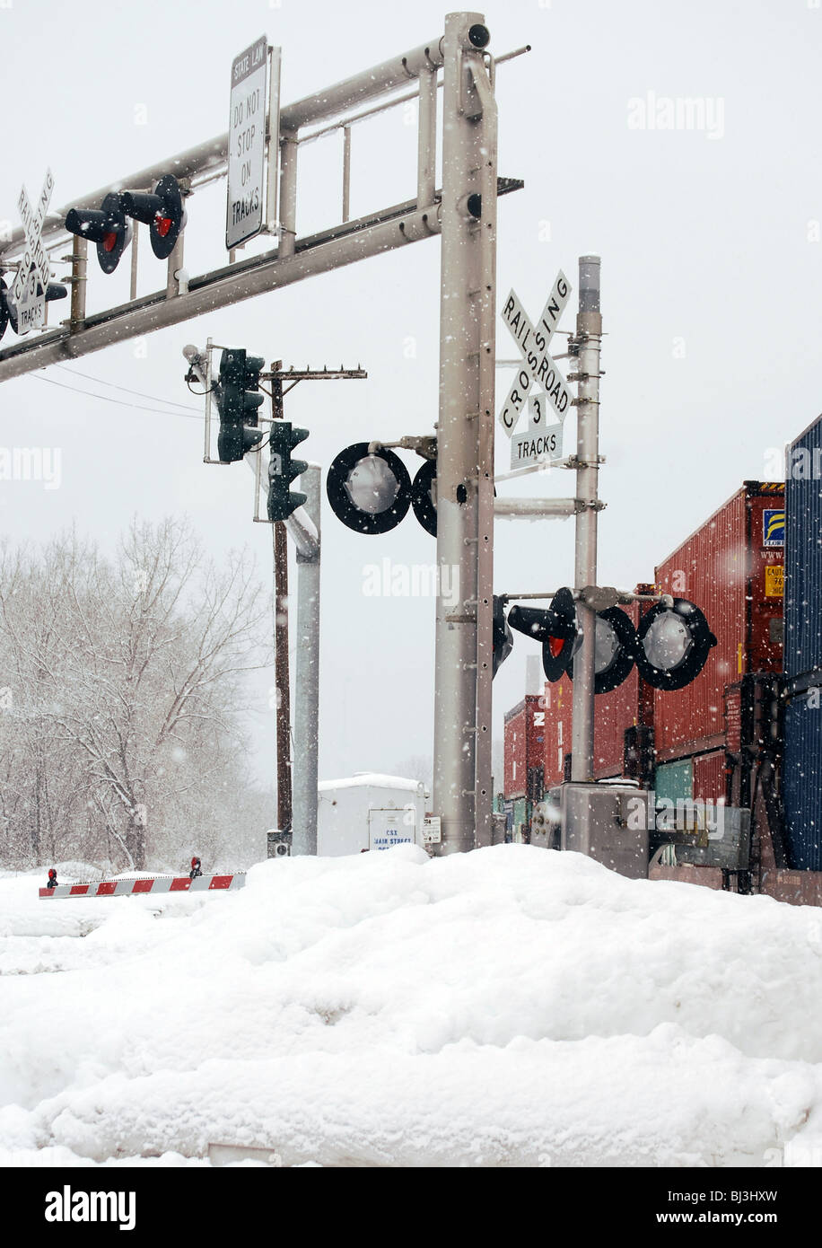 CSX freight train passes road railroad crossing intersection. Barrier ...
