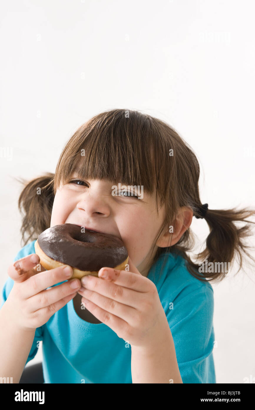 A girl biting into a donut with pleasure Stock Photo - Alamy