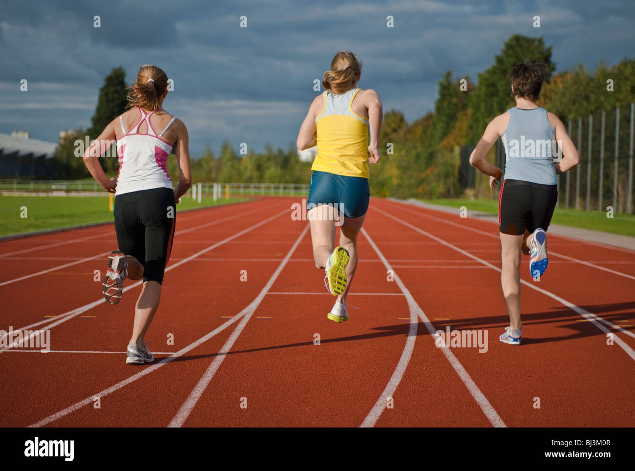 3 female athletes running away Stock Photo - Alamy