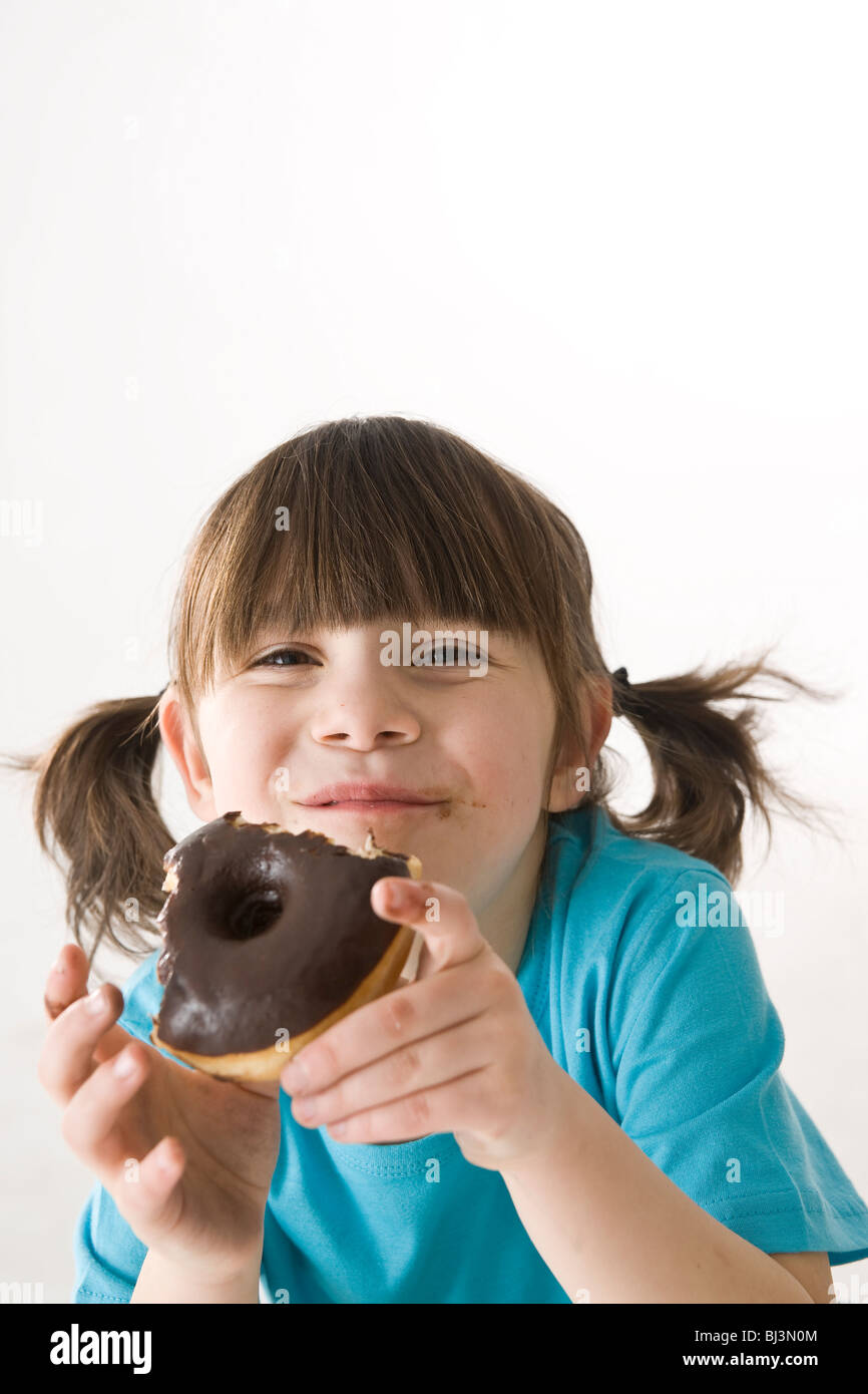Girl biting into a donut with pleasure Stock Photo - Alamy