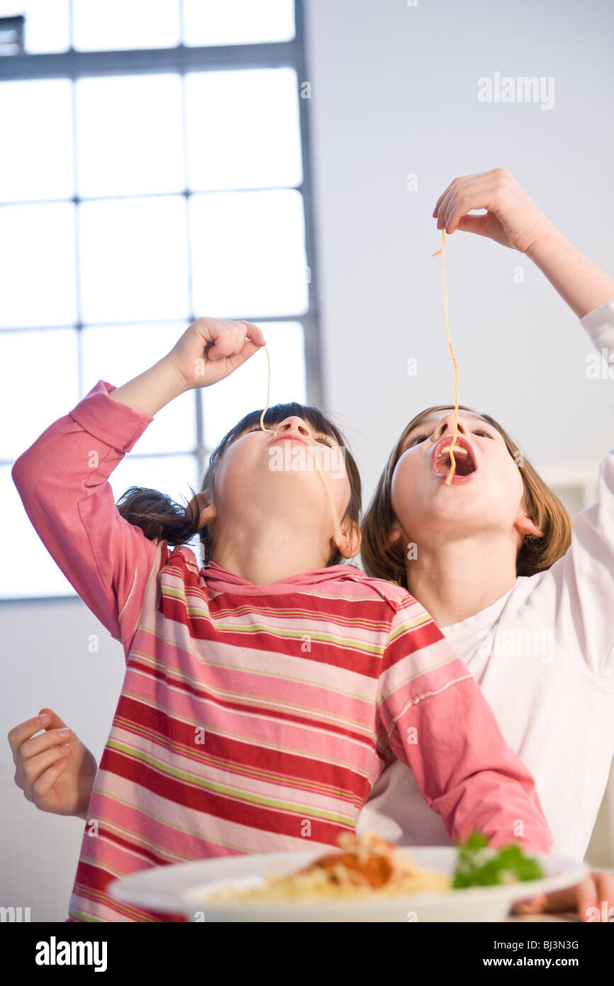Two girls eating spaghetti together Stock Photo - Alamy