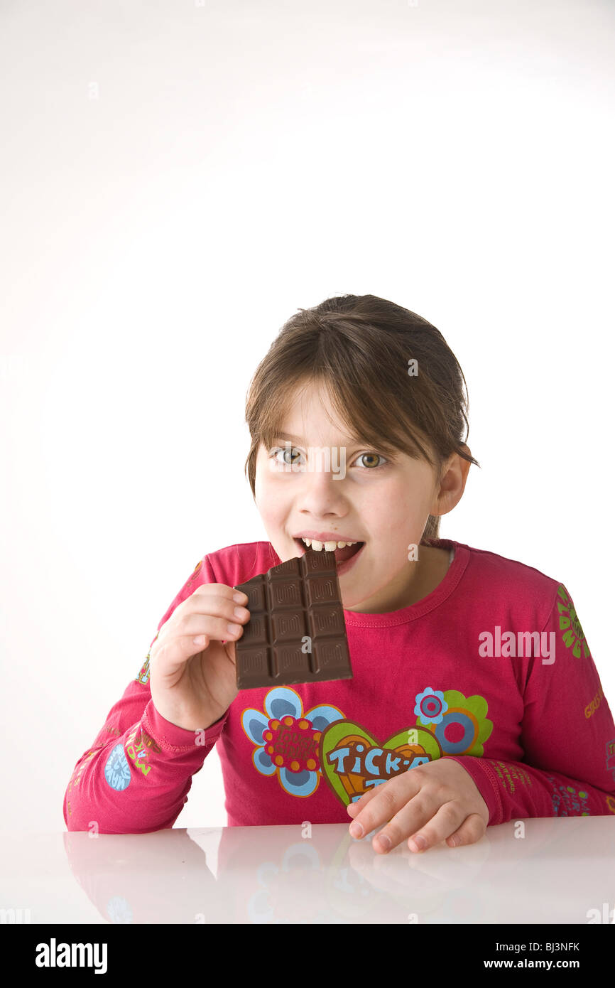 Girl biting into a chocolate bar with pleasure Stock Photo - Alamy