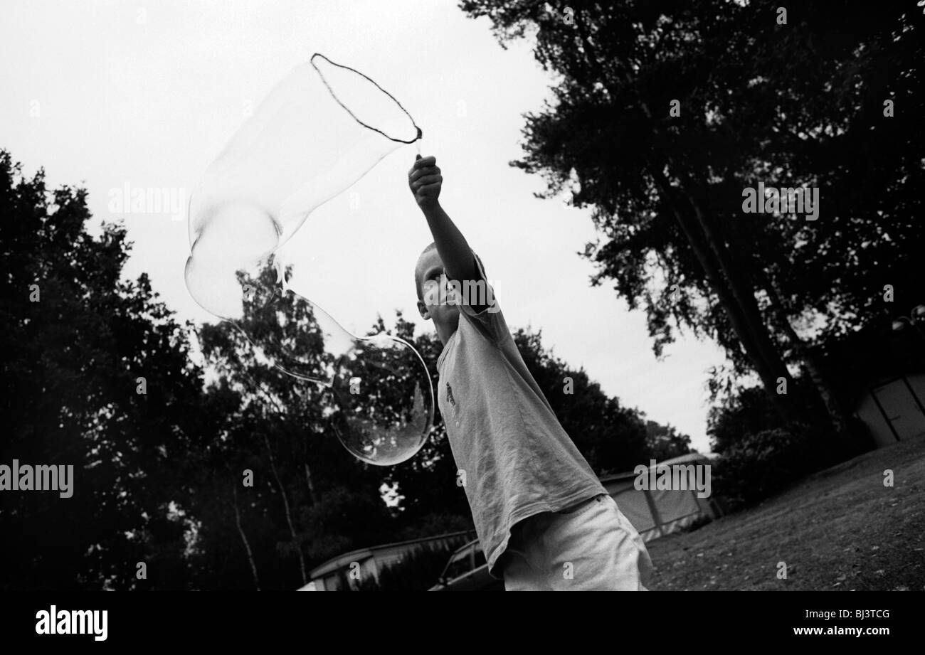 Reaching high above his head, a young four year-old boy waves a hoop ...
