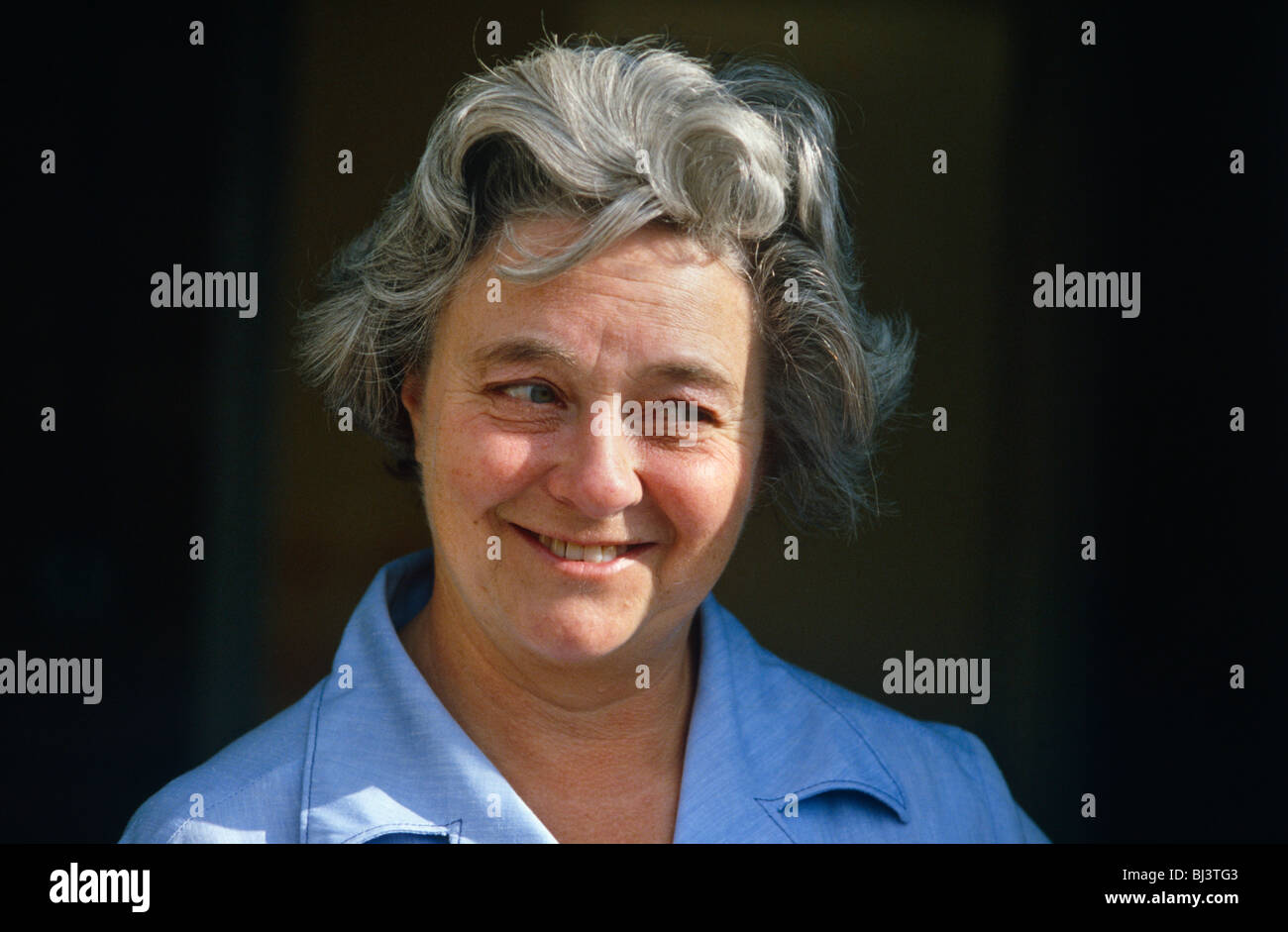 A wrinkled English Caucasian lady in her sixties, smiles at something ...