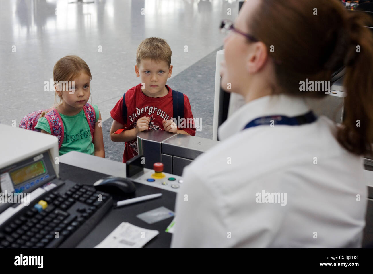 Young brother and sister look on in awe while a British Airways check ...