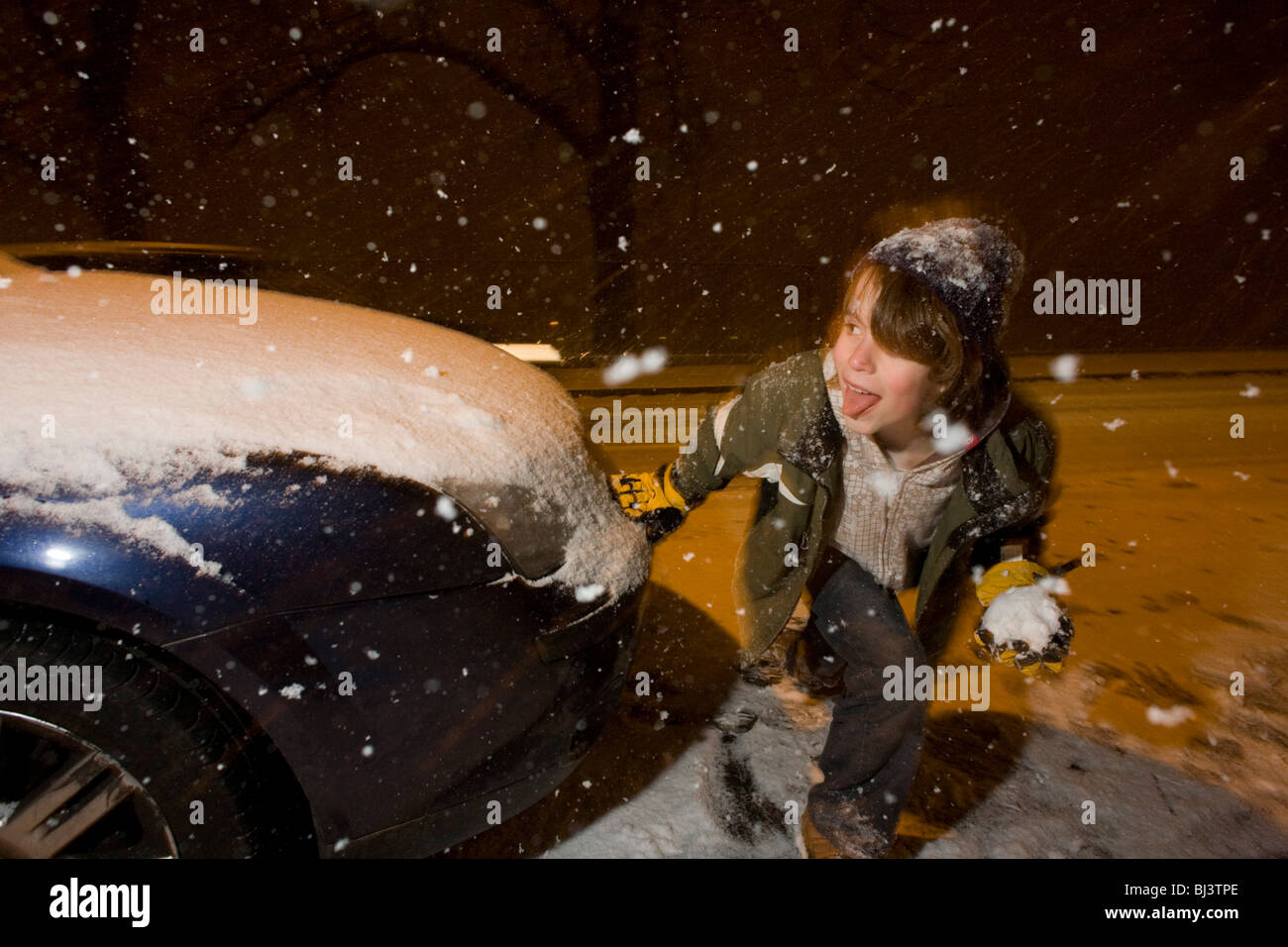 A boy plays snowballs at night during heavy snow showers in central ...
