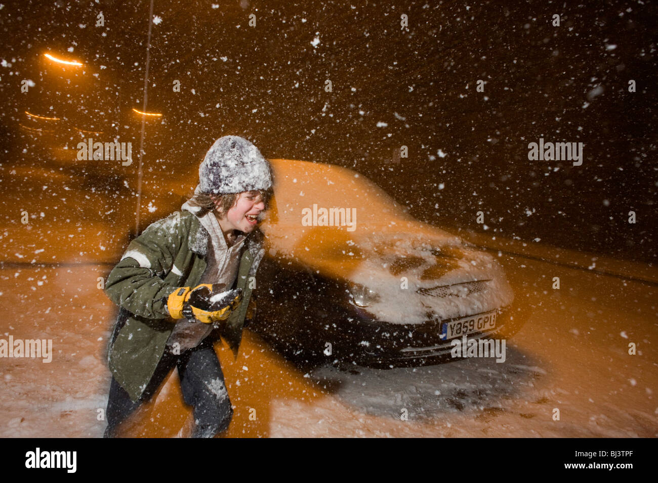 A boy plays snowballs at night during heavy snow showers in central ...