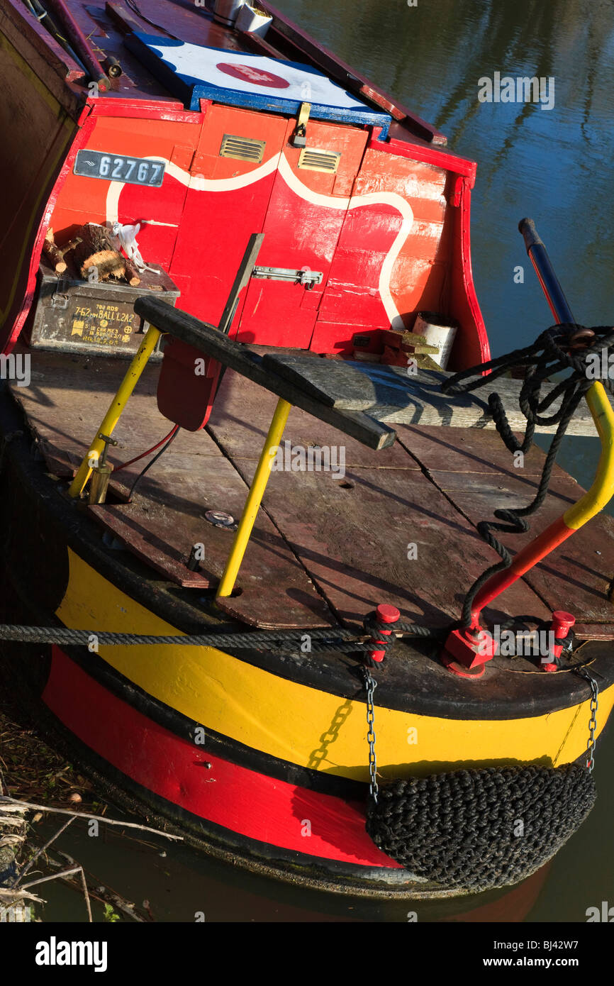 The stern of a brightly Coloured red and yellow canal long boat moored ...