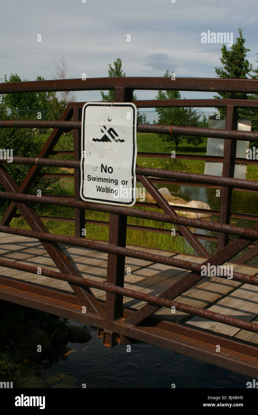 No swimming or wading sign on the rail of a foot bridge over a creek ...