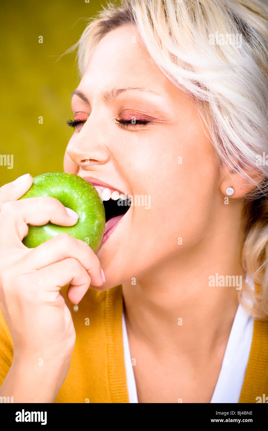 Young woman biting into apple Stock Photo - Alamy