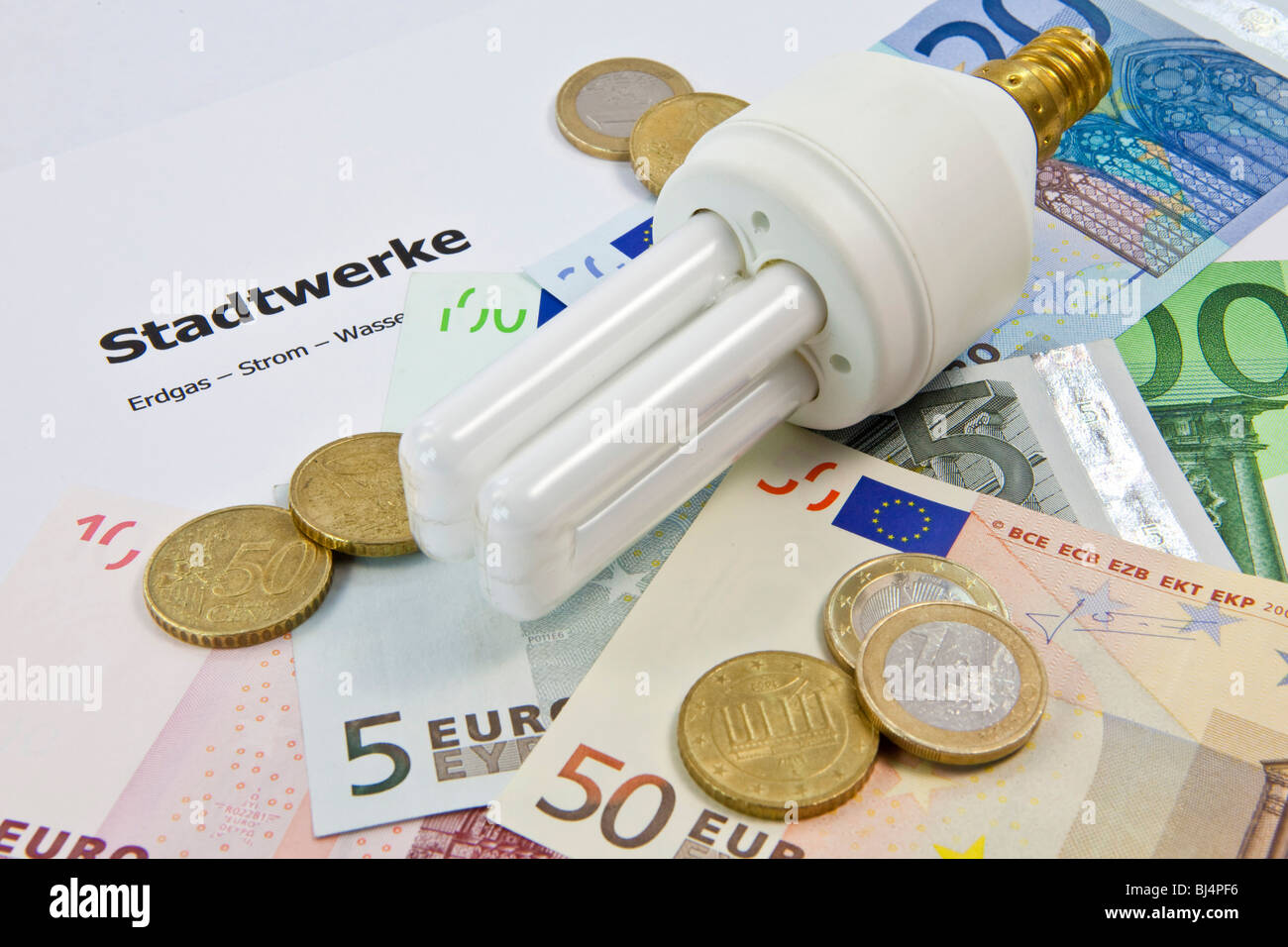 Energy saving lamp, banknotes, coins, high costs Stock Photo - Alamy