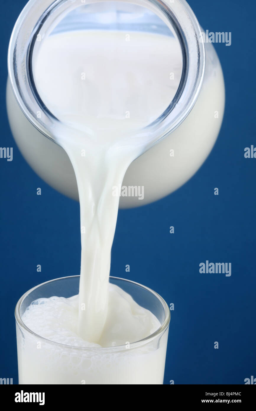 Milk pouring from jar into the glass Stock Photo - Alamy