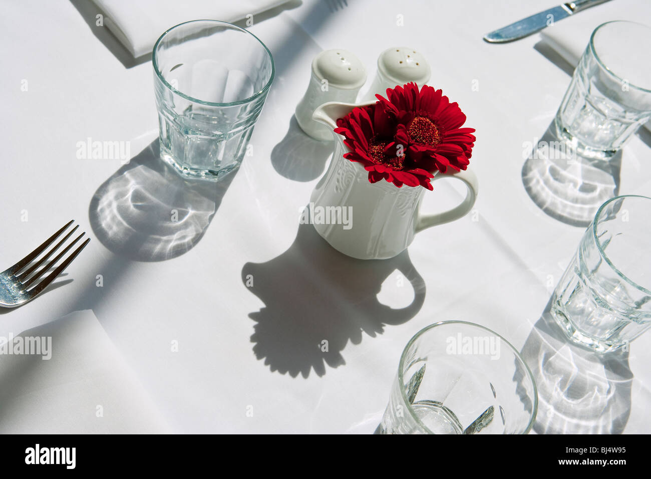 single place table setting accented with red flowers Stock Photo - Alamy