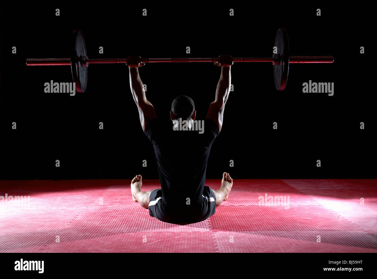 man lifting weight bar whilst sitting Stock Photo - Alamy
