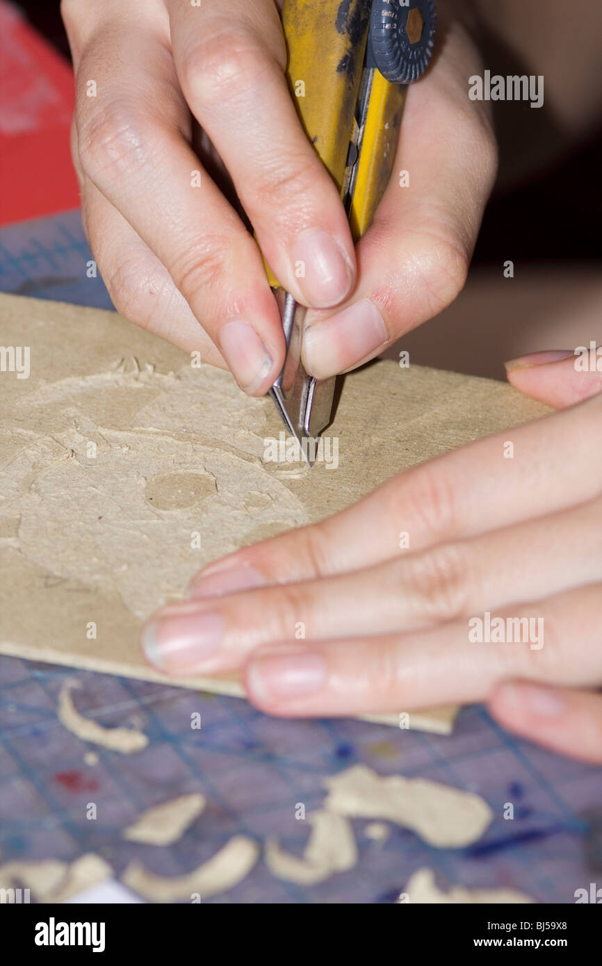 Artist using a Razor Blade Knife to cut an engraving into book board ...
