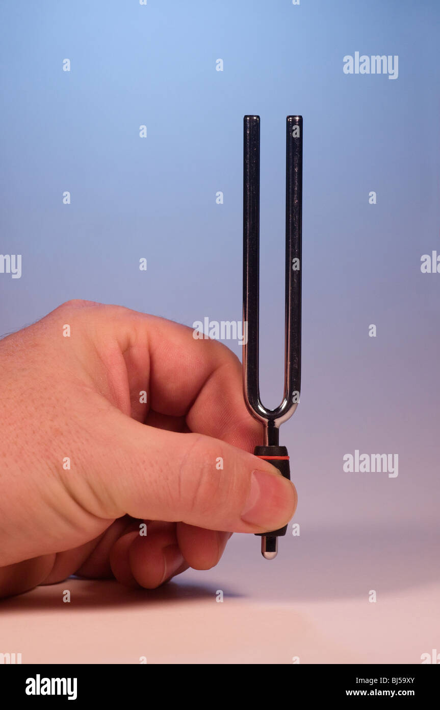 Man's hand holding a tuning fork Stock Photo - Alamy
