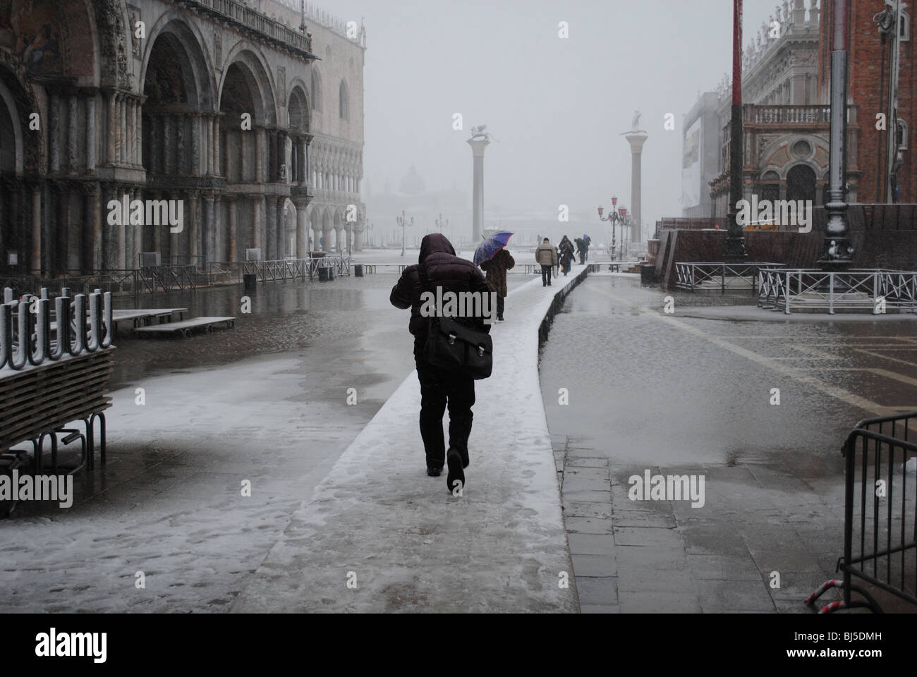 People walk along an icy walkway in a snow storm, in front of St Mark's ...