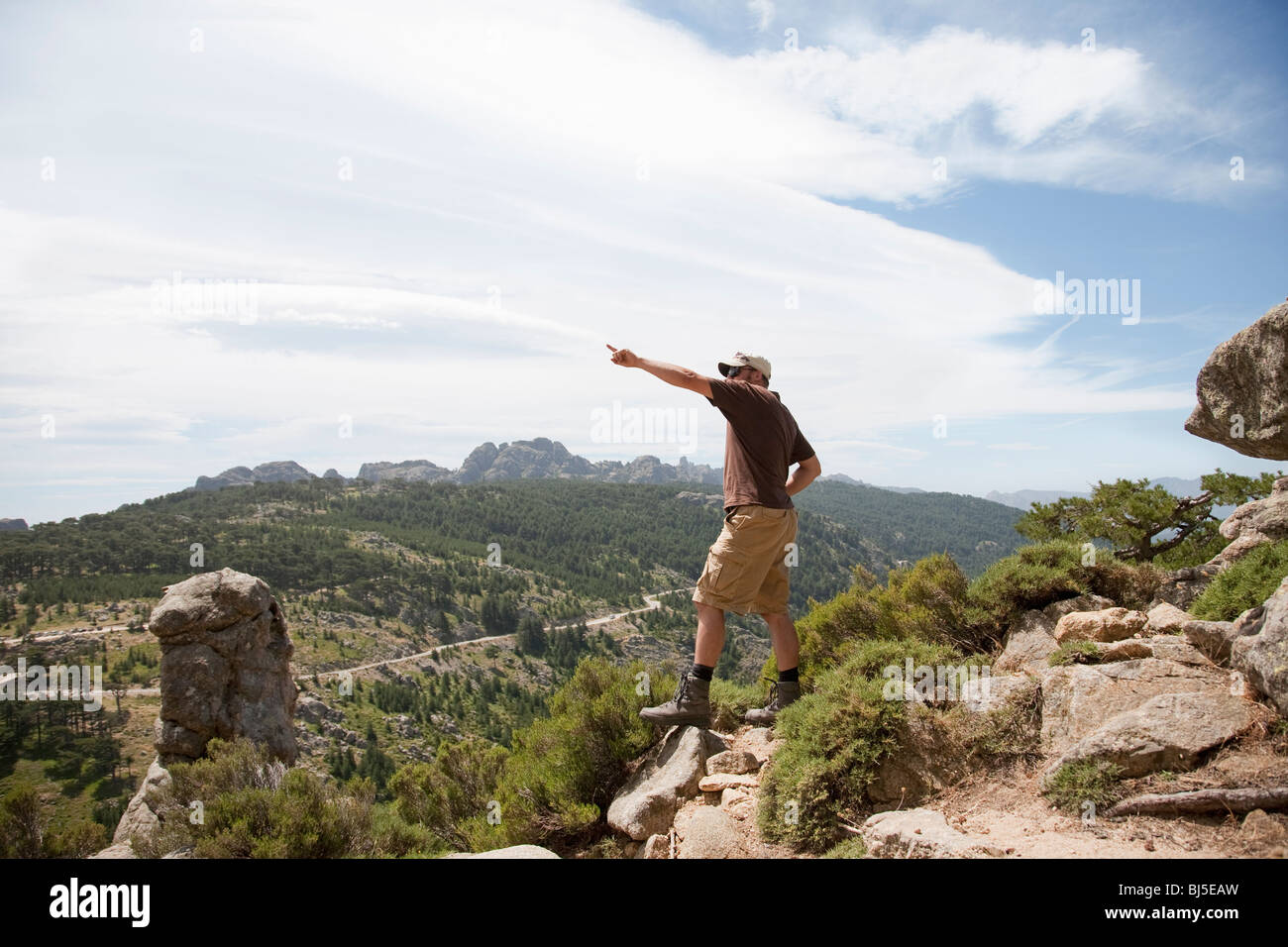 Man on a cliff pointing Stock Photo - Alamy