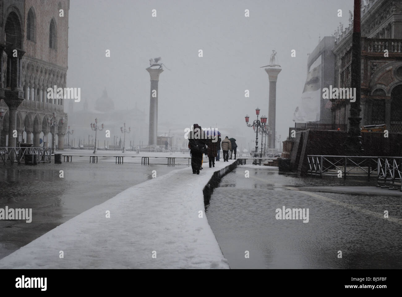 People walk along an icy walkway in a snowstorm, in front of the Doge's ...