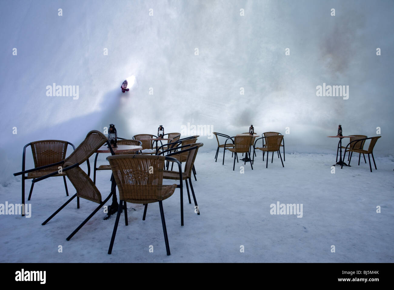 Young child looking inside to a snow cafe from a hole in the thin snow ...
