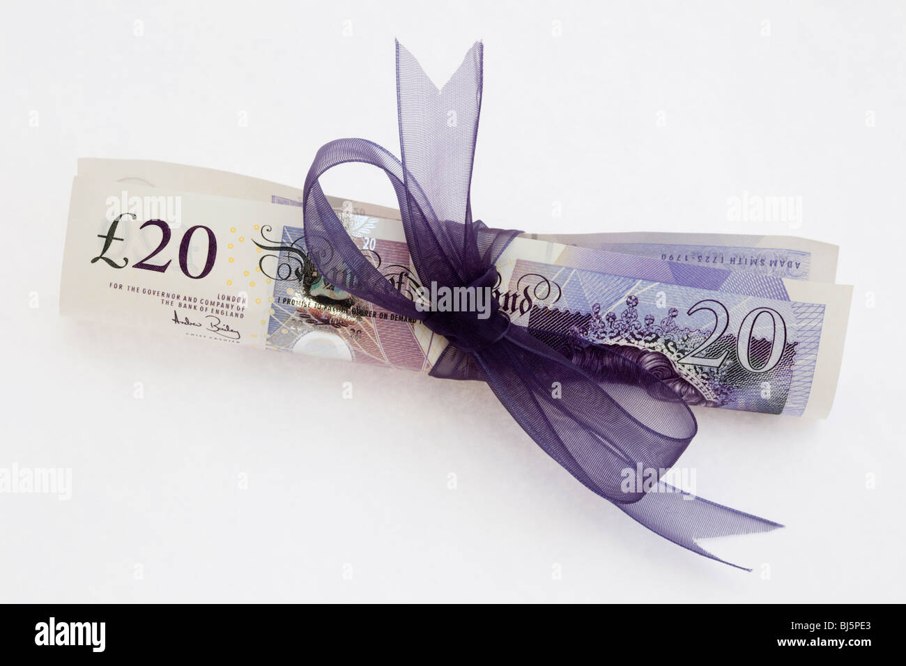 Rolled up old sterling £20 pound note GBP tied up with a purple ribbon ...