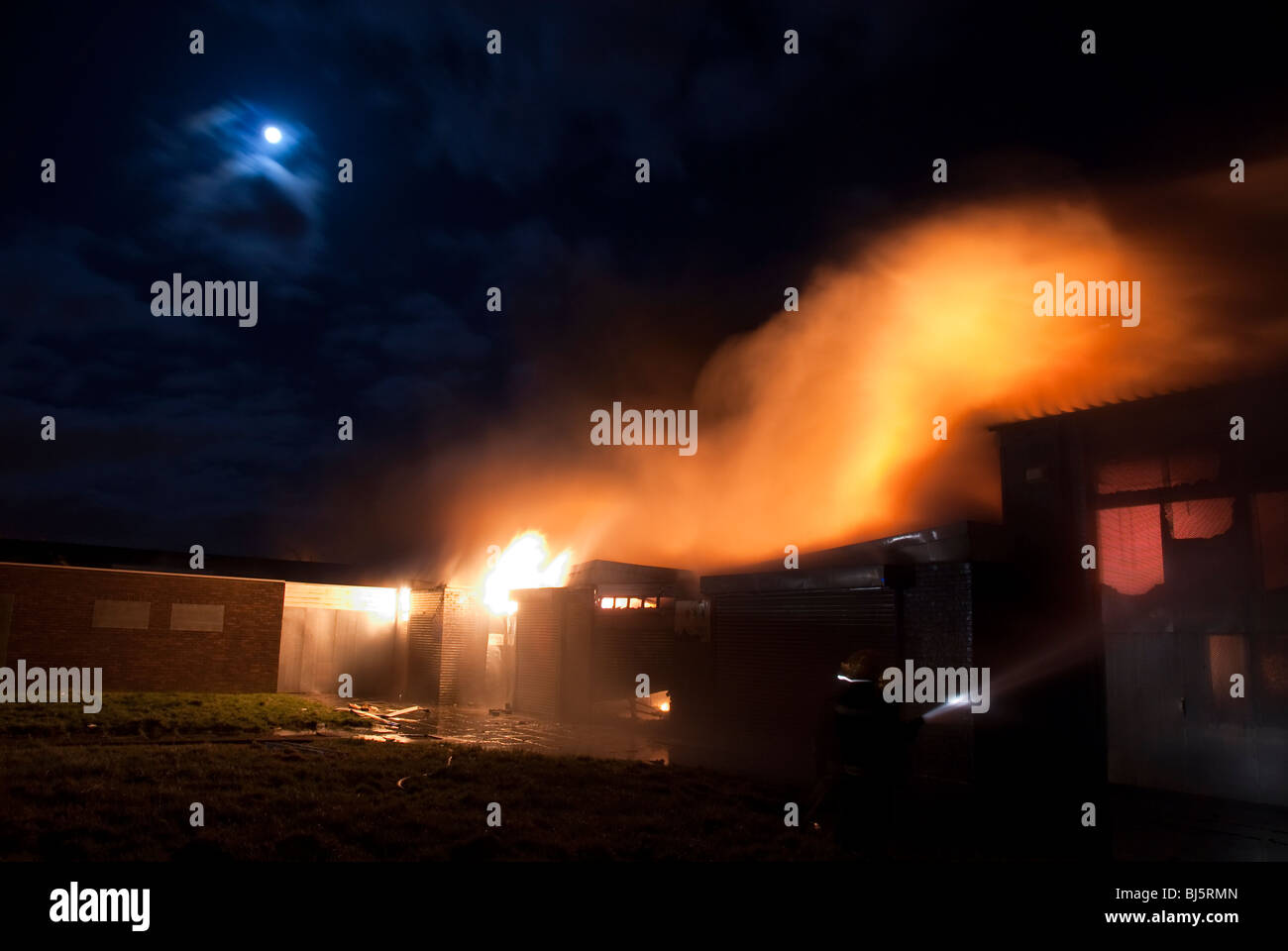 School on fire at night with flames, smoke and moon in background Stock ...