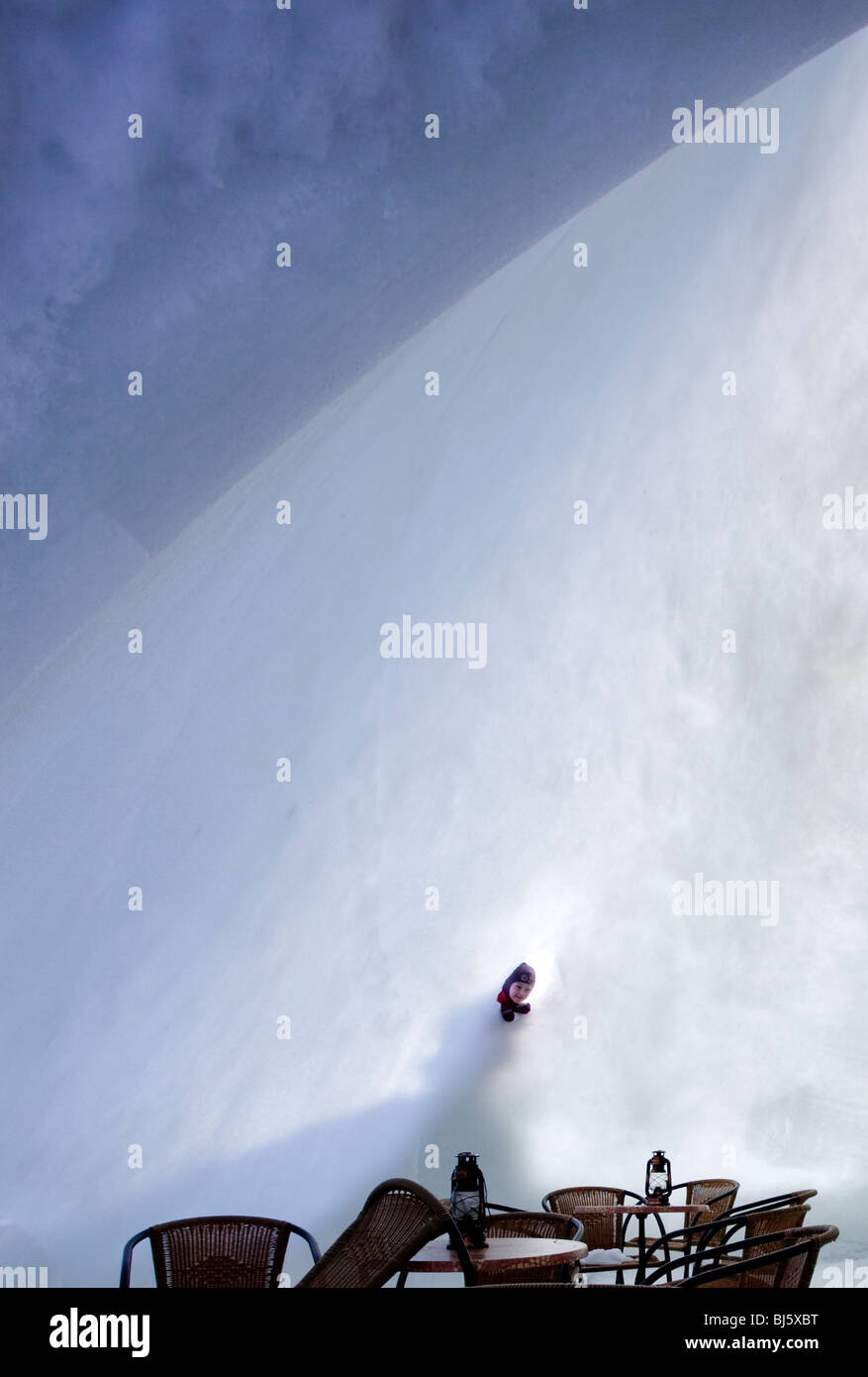 Young child looking inside to a snow cafe from a hole in the thin snow ...