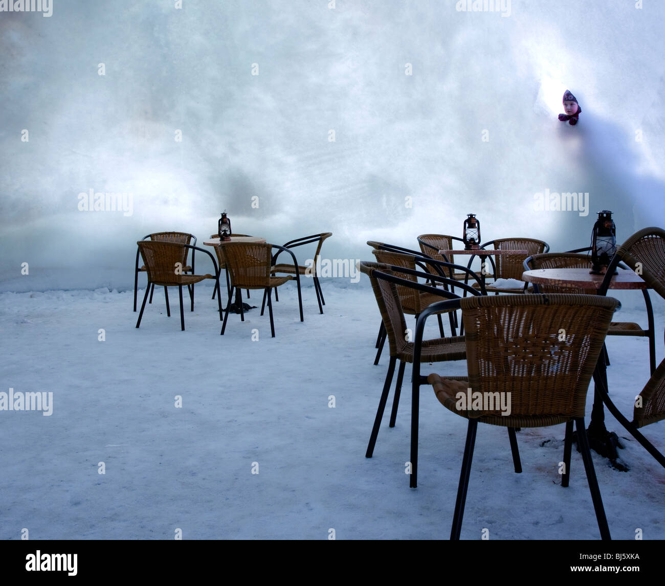 Young child looking inside to an empty snow cafe from a hole in the ...