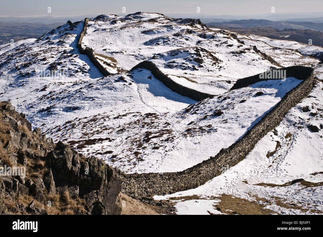 Snow covered fell top with dry stone wall running along a ridge ...