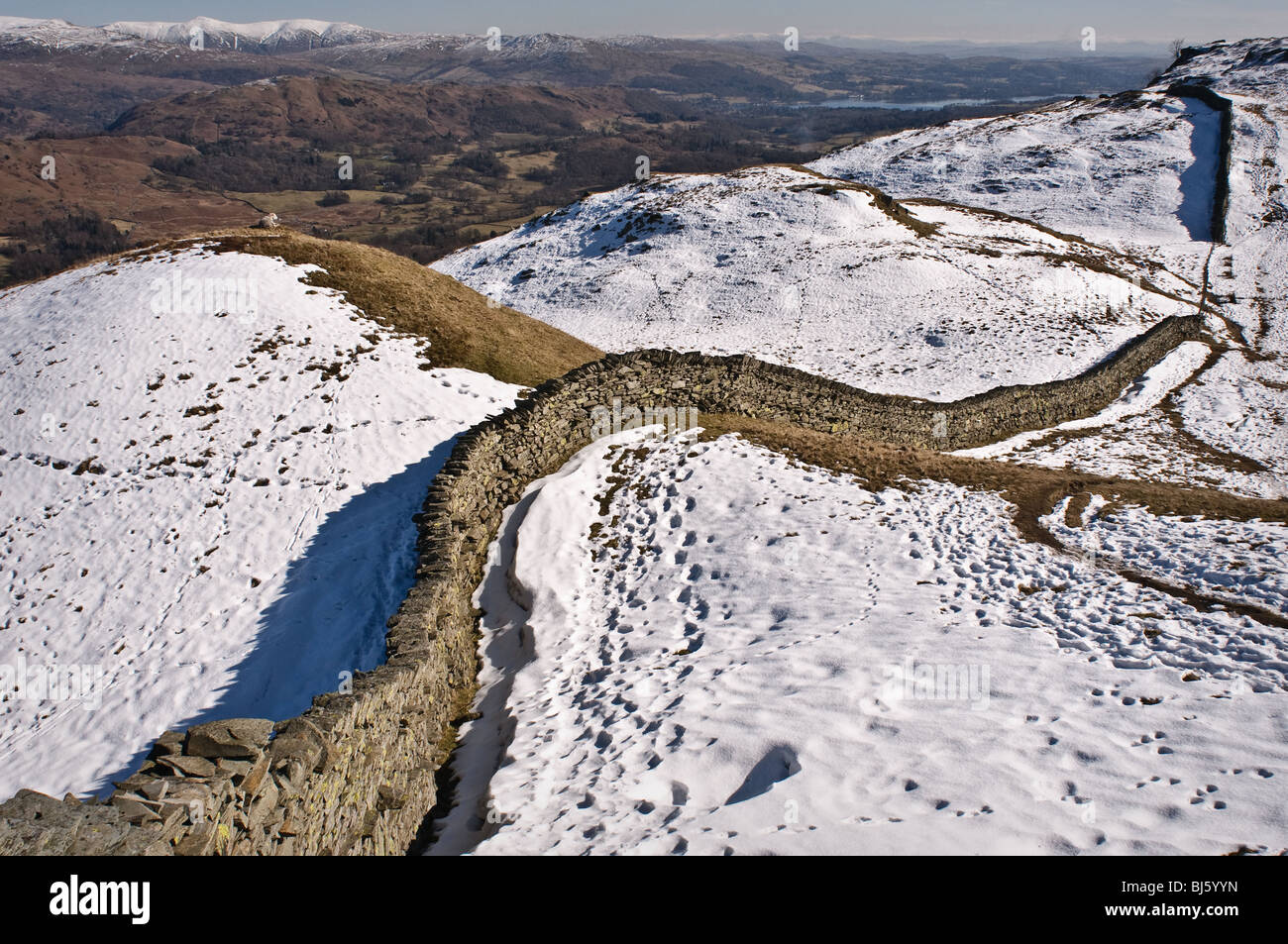 Snow covered fell top with dry stone wall running along a ridge ...