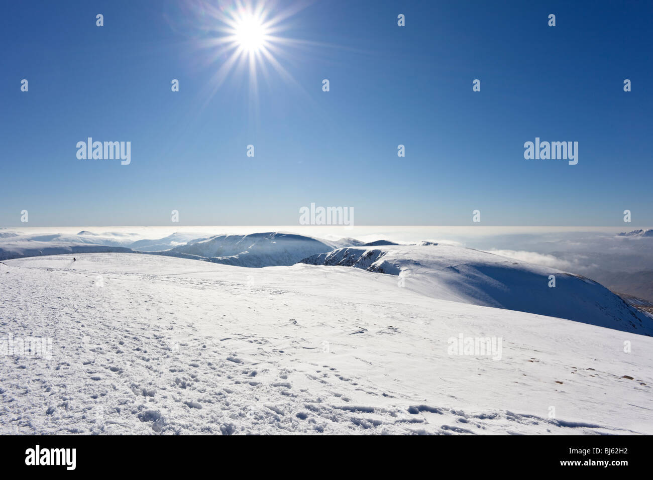 Bright sunshine above the snow covered summit plateau of Helvellyn ...