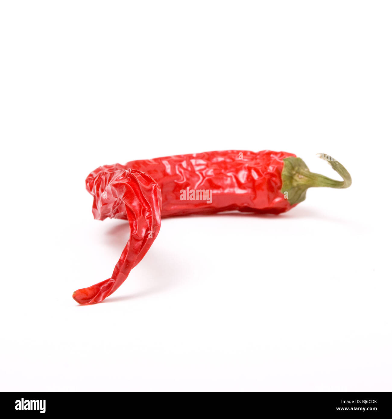Wrinkled vibrant red chilli's isolated against white background with ...