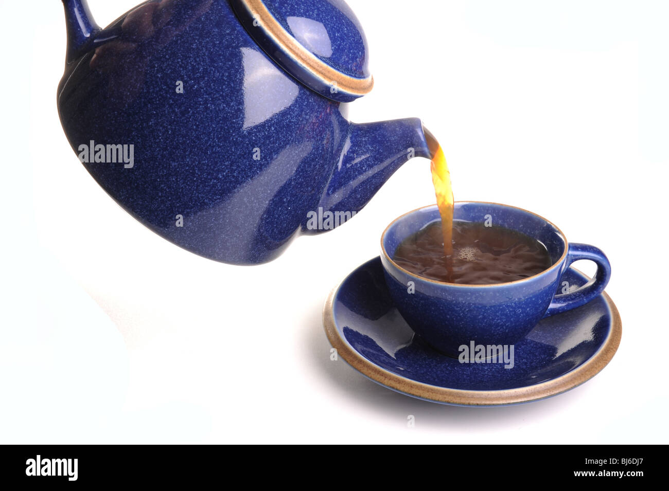 Tea pot pouring tea into a teacup, studio isolated Stock Photo - Alamy
